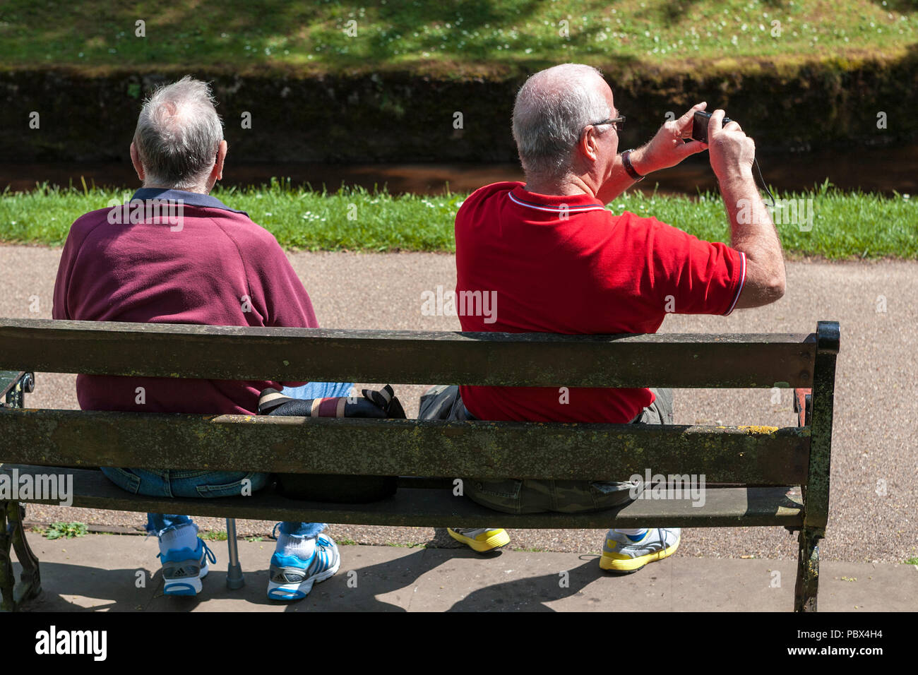 Two old men sit on a park bench, Pavilion Gardens, Buxton, Derbyshire ...