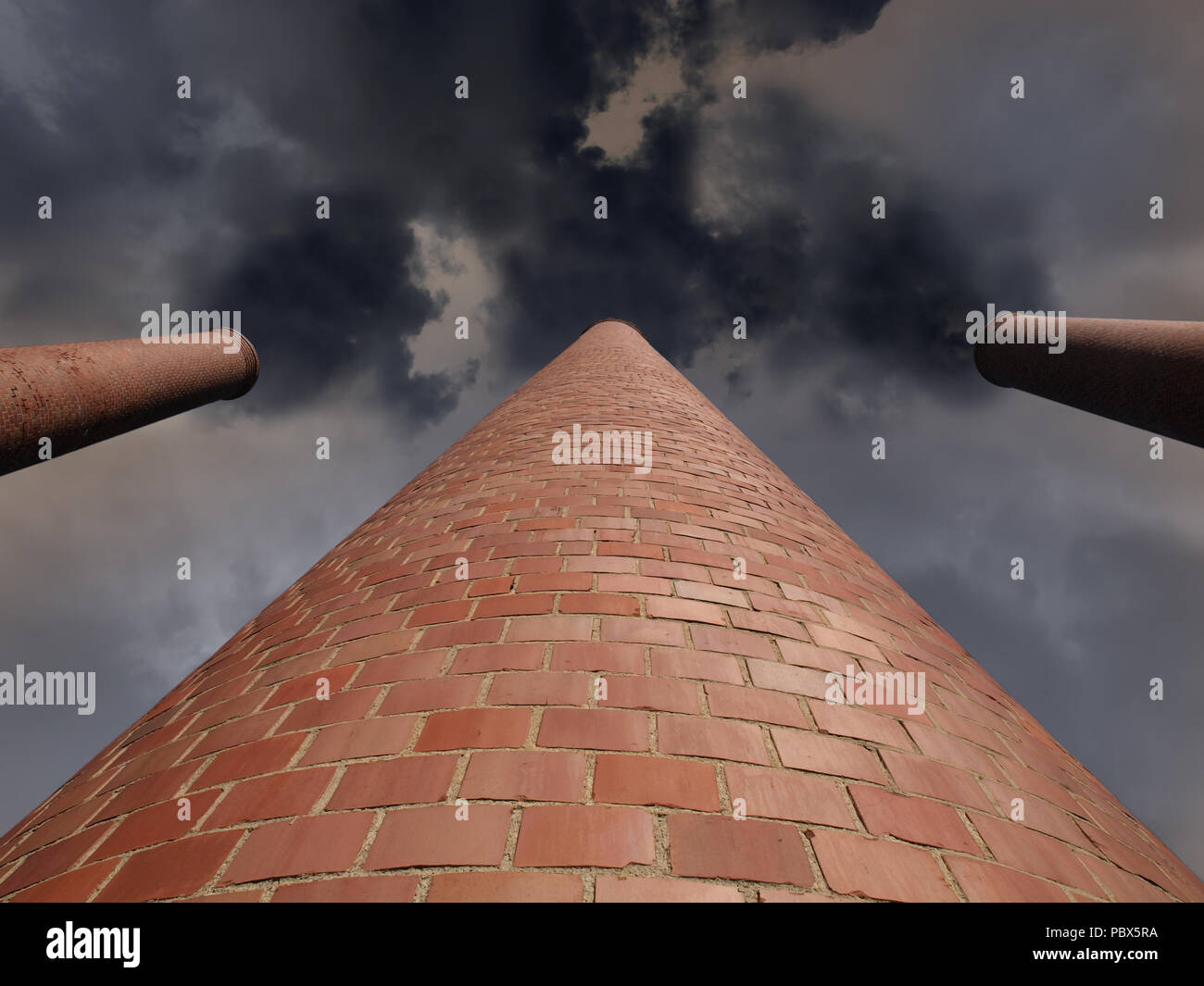 Three billowing brick smokestacks with dark stormy sky Stock Photo - Alamy