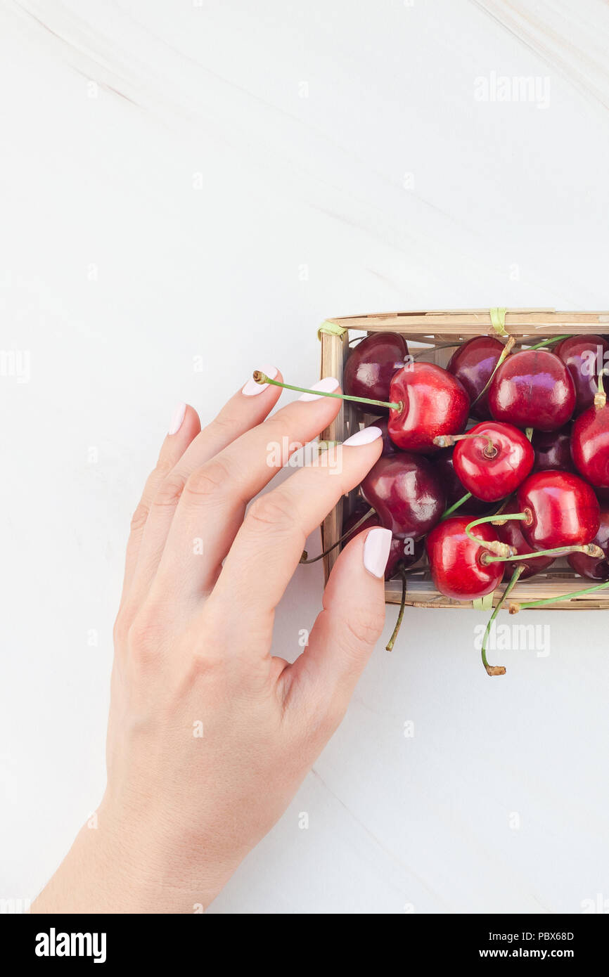 Creative top view of fresh ripe cherry in a small wicker basket with ...