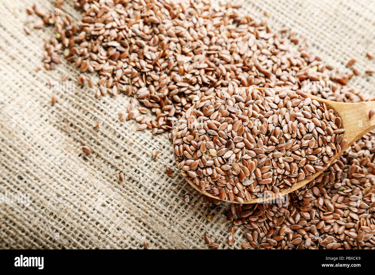 The seeds of flax are scattered on the table, on a linen napkin. Seeds in a wooden spoon ...