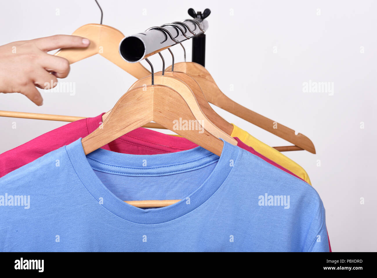 Male hand taking a hanger for clothes from shelf isolated over white ...