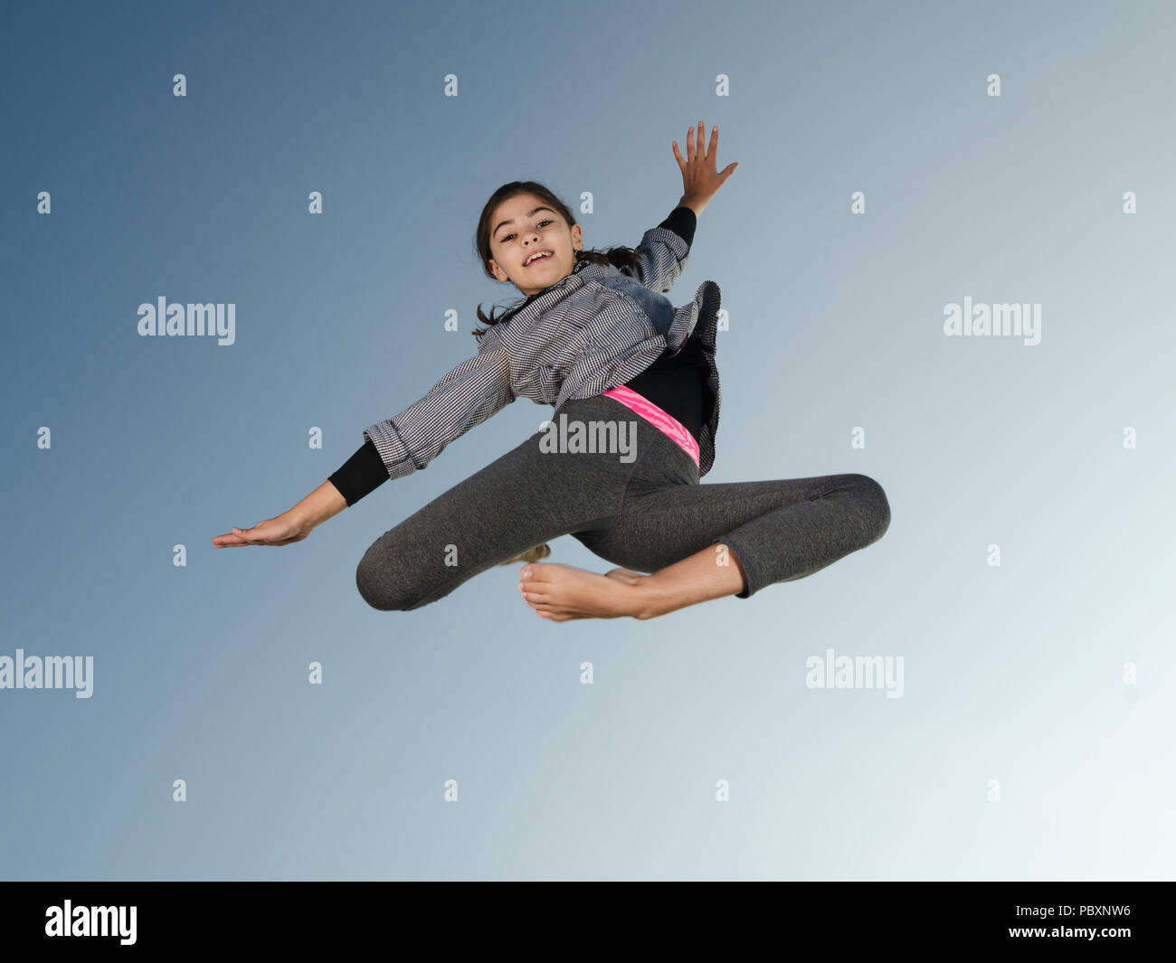 Smiling, happy young girl gymnast acrobat jumping high in the sky Stock ...