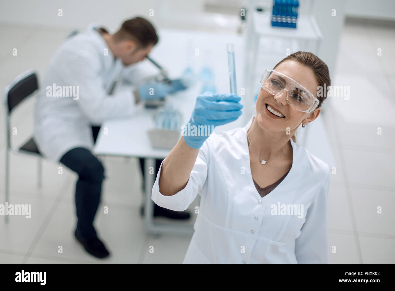 serious female scientist looks at the tube with the results of the ...