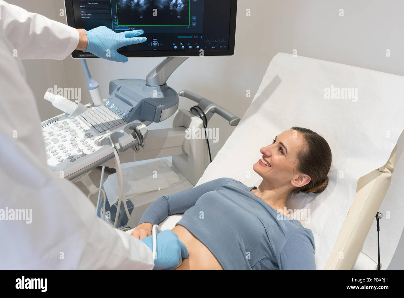 Woman and doctor looking at ultrasonic screen during examination Stock ...