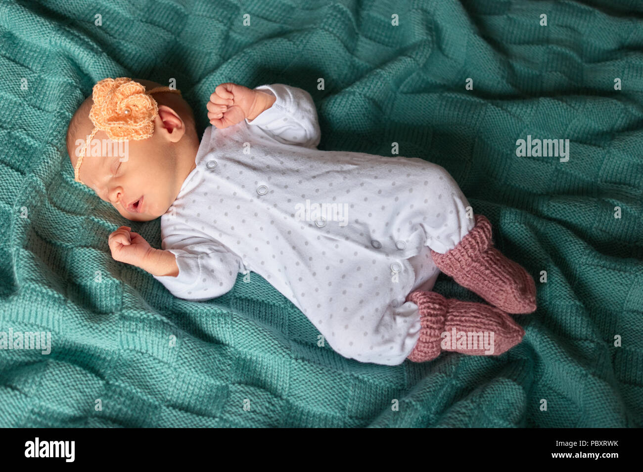 Sleeping Newborn Baby. Green warm clothes background Stock Photo - Alamy