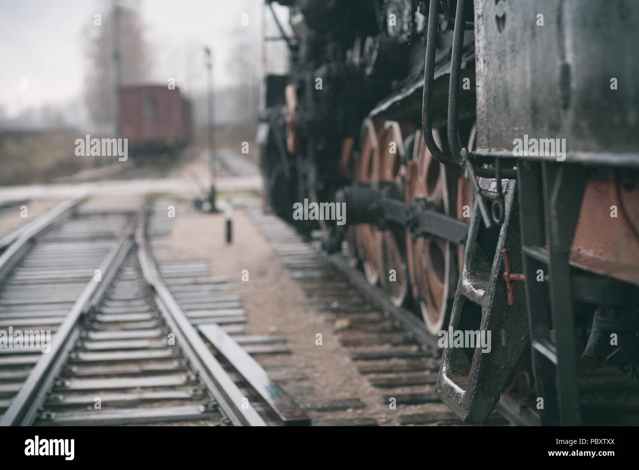 Steel stairs in Vintage steam train on wet rails of the railway station ...