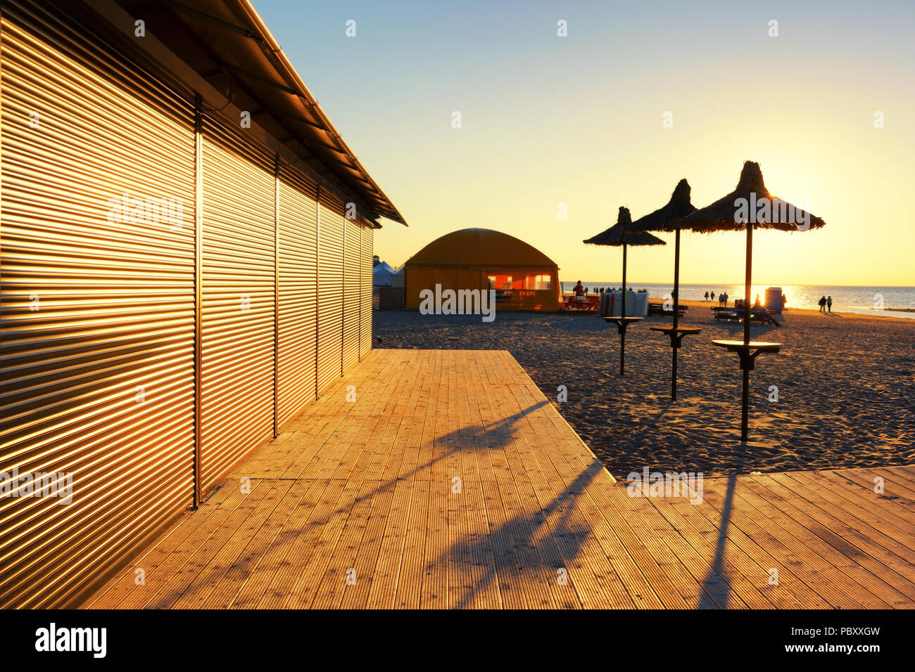 Wooden terrace with beach umbrellas and a cafe in the sunlight and ...