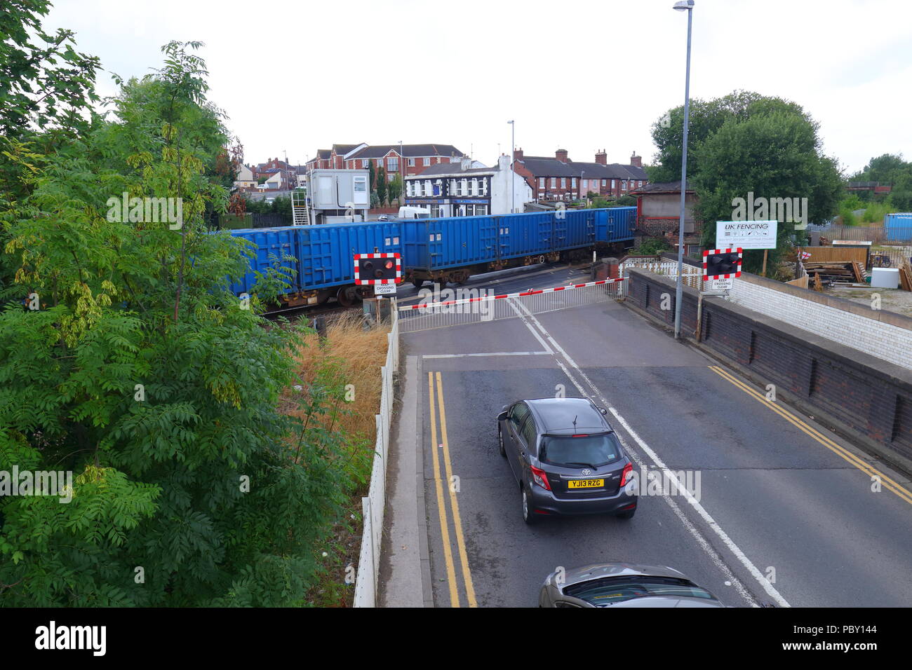 A freight train passes over a level crossing between High Street ...