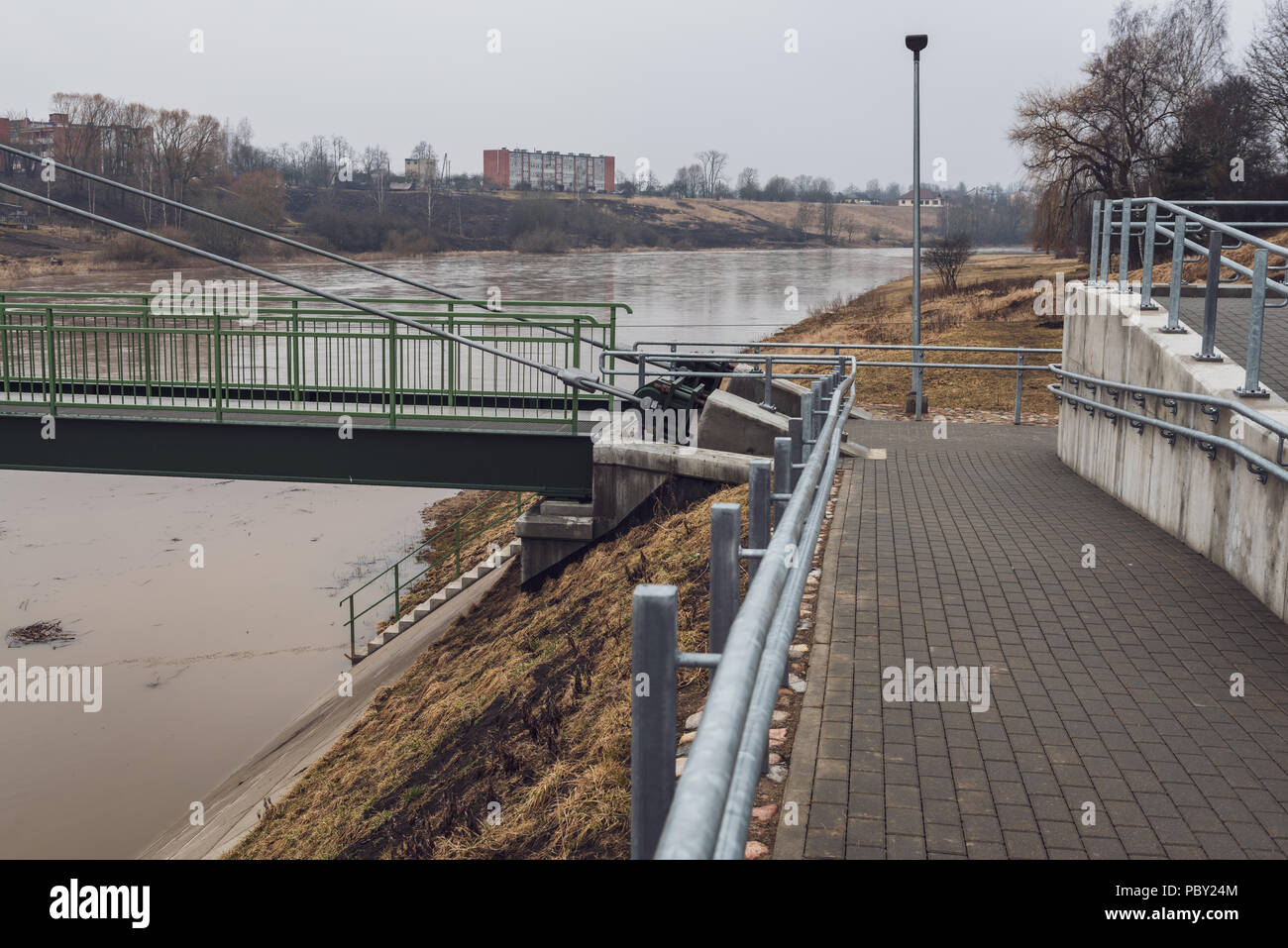 brand new metal bridge with shiny rails and concrete steps. cloudy ...