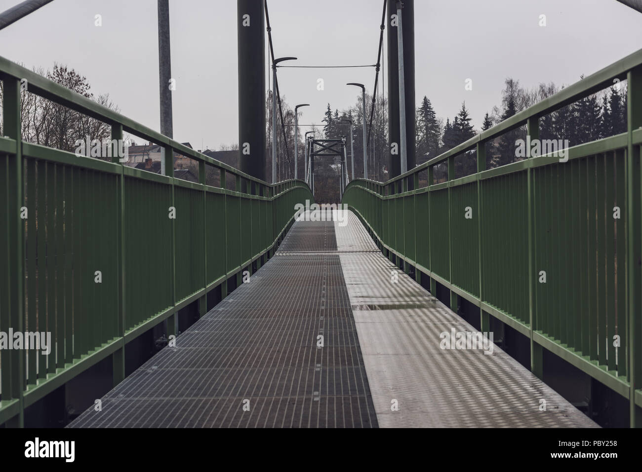 brand new metal bridge with shiny rails and concrete steps. cloudy ...