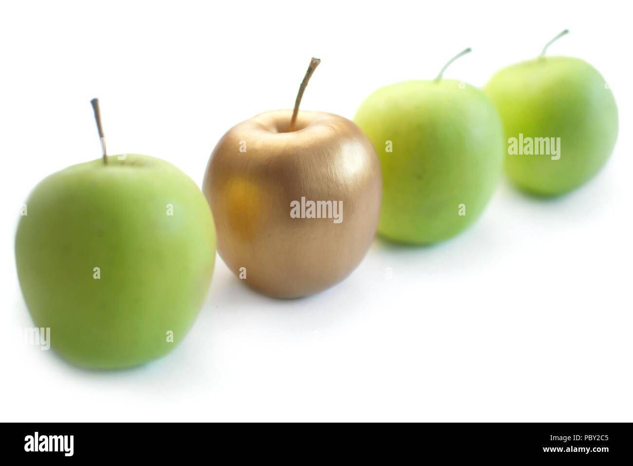 Gold apple standing out in a line of green Stock Photo - Alamy