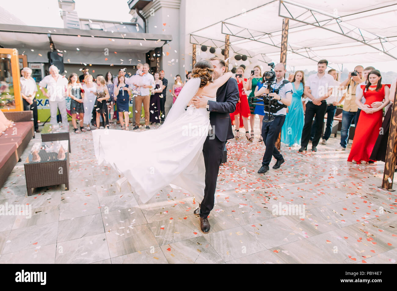 Happy dancing couple. Groom is swaying the bride round in the rain of ...