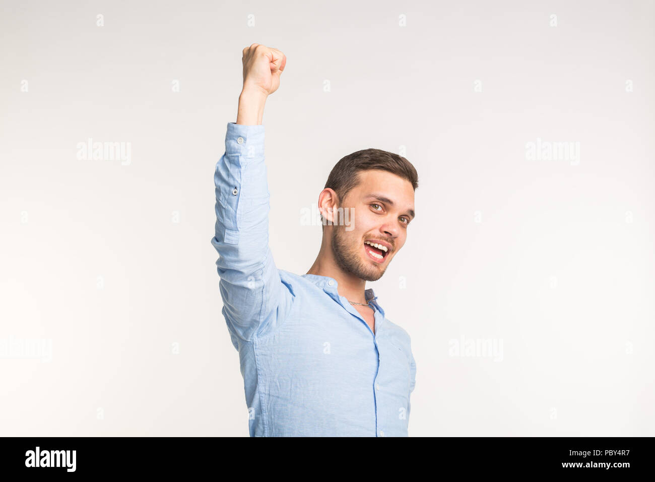 Victory and power concept - Handsome man raising one hand above his ...