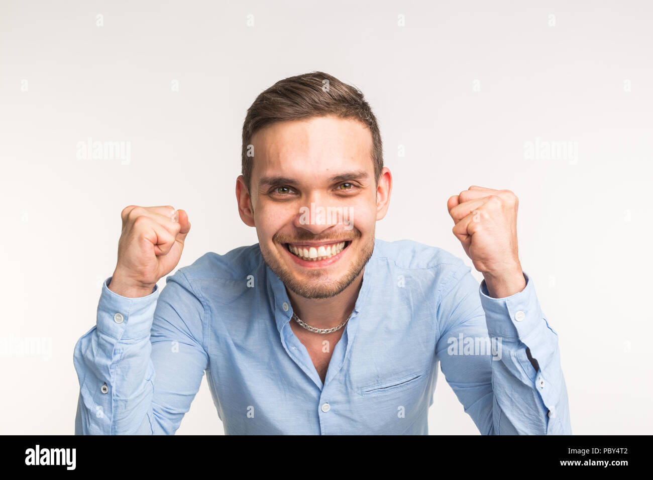 Emotions and people concep t- young happy man raised his fists up over ...