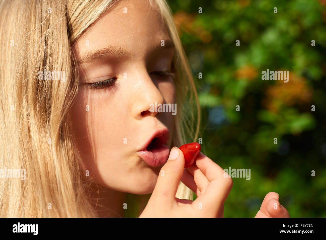 Child cute girl holding fresh raw chilli pepper and preparing to eat it ...