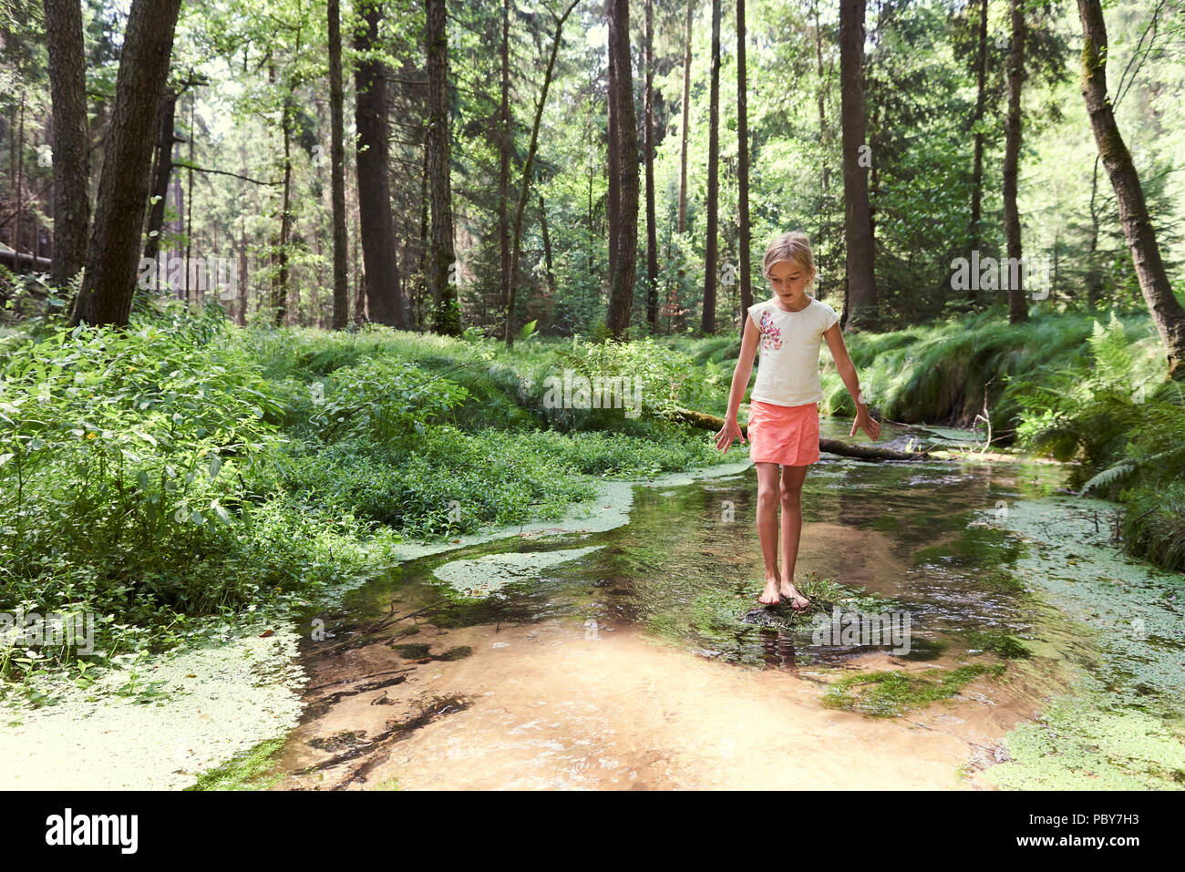 Child cute blond girl playing in the creek. Gril walking in forest ...