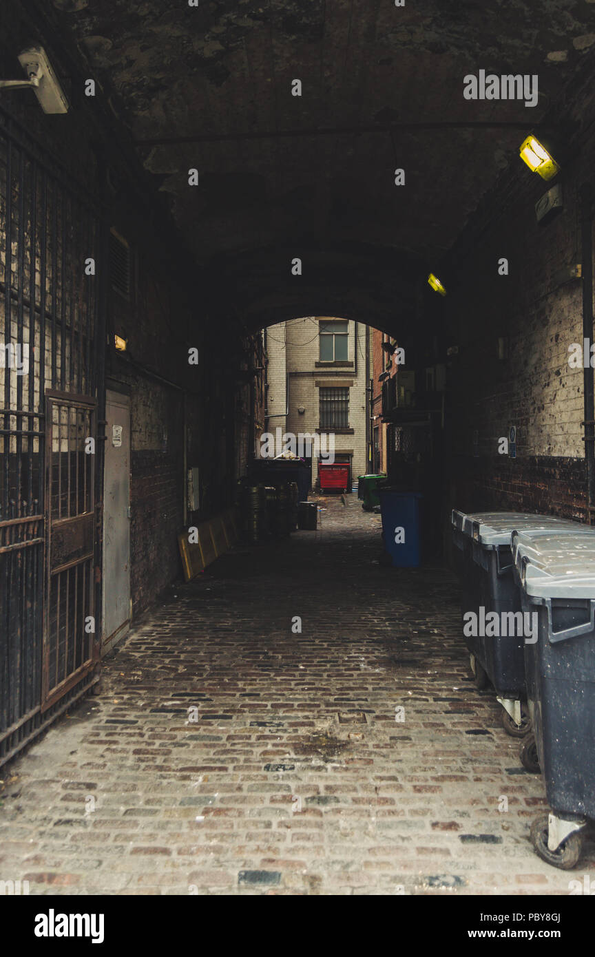 Dark and old alley. Creepy passage with trash bins, windows and ...