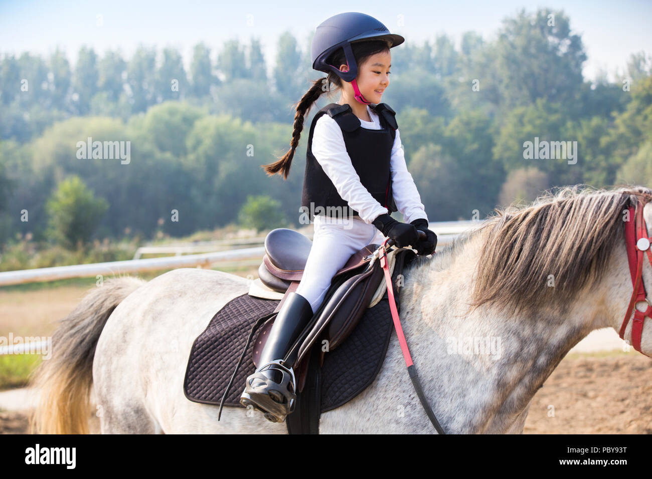 Cheerful little Chinese girl riding horse Stock Photo - Alamy