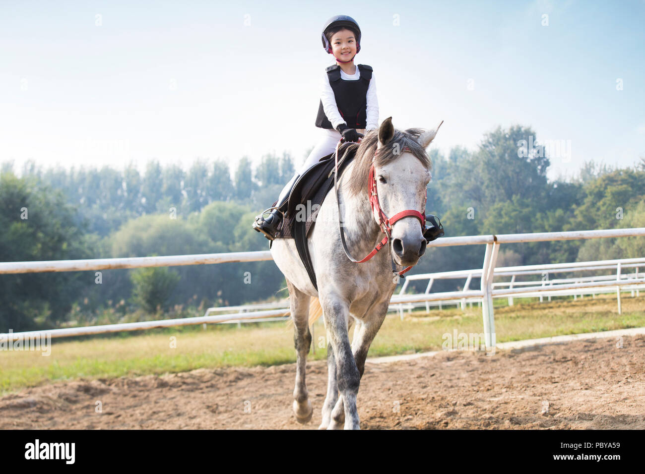 Cheerful little Chinese girl riding horse Stock Photo - Alamy