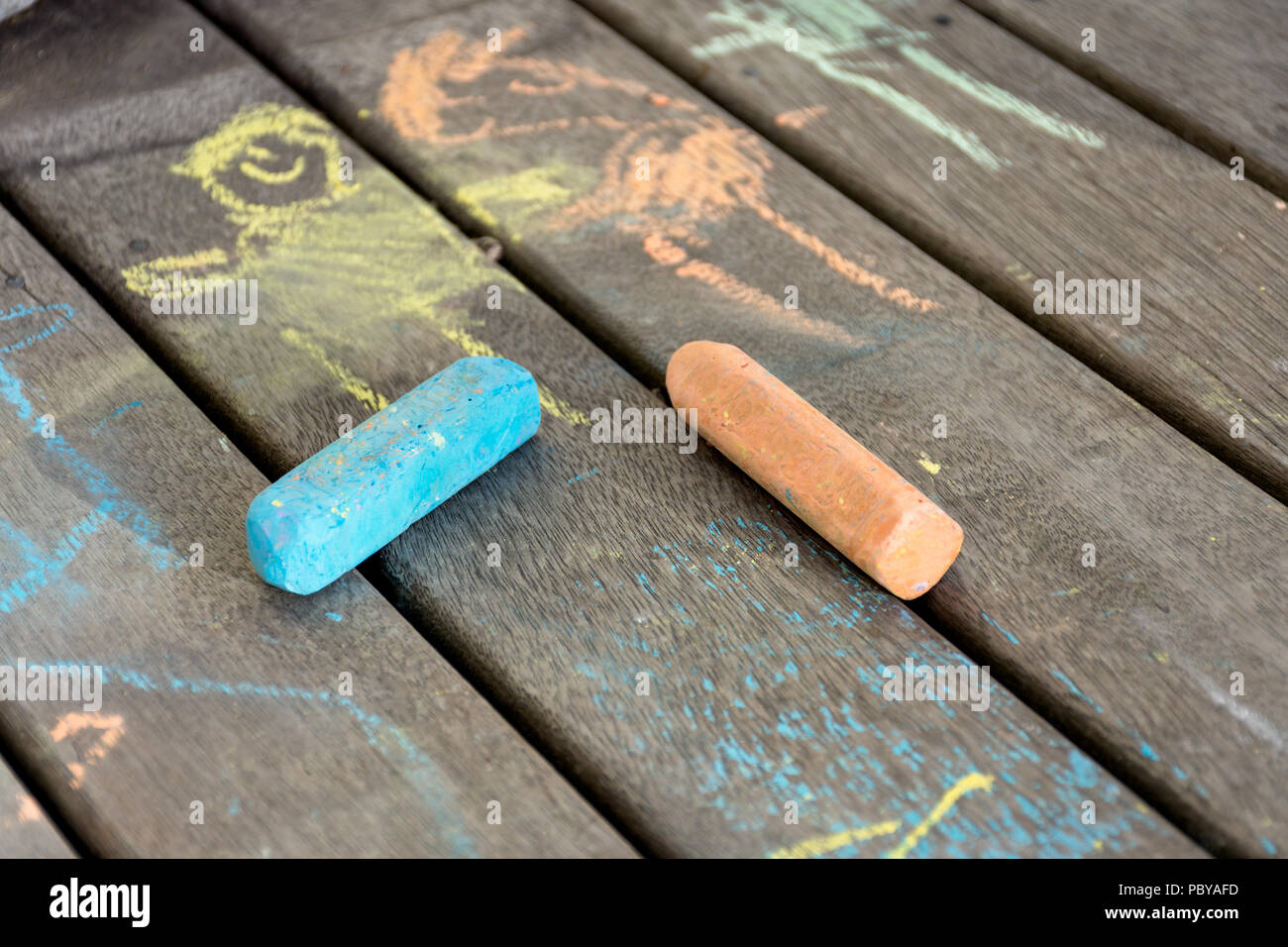 Yellow and orange chalk and a child's chalk drawings of people on a ...