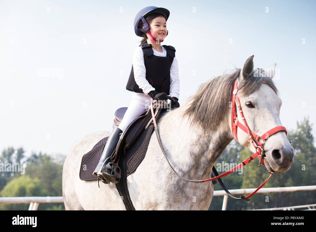 Cheerful little Chinese girl riding horse Stock Photo - Alamy