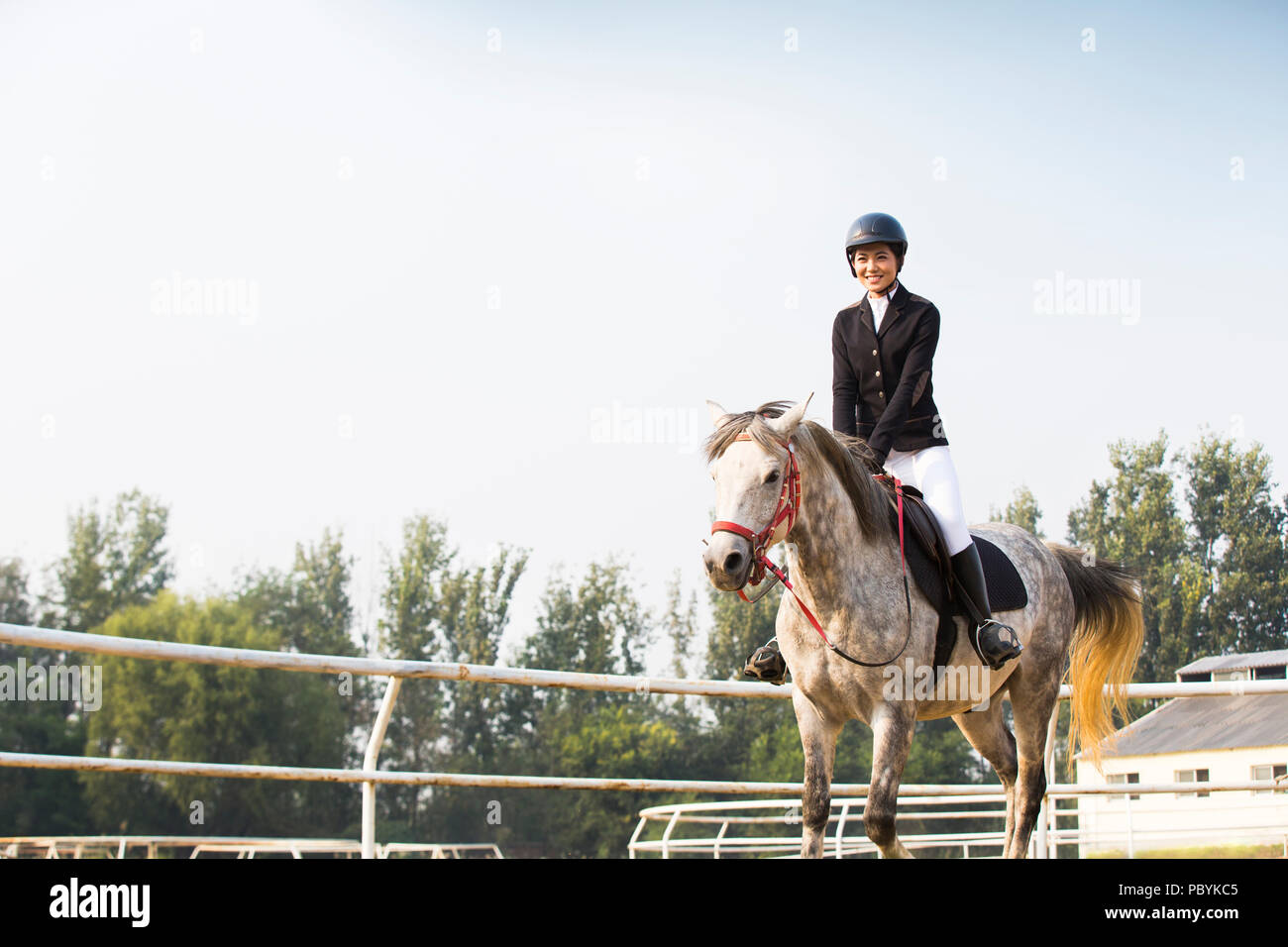 Cheerful young Chinese woman riding horse Stock Photo - Alamy