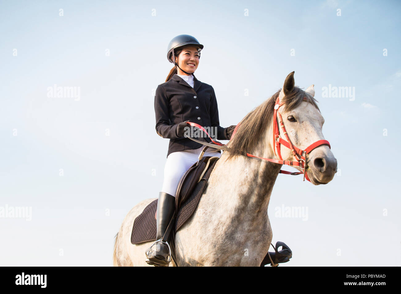 Cheerful young Chinese woman riding horse Stock Photo - Alamy
