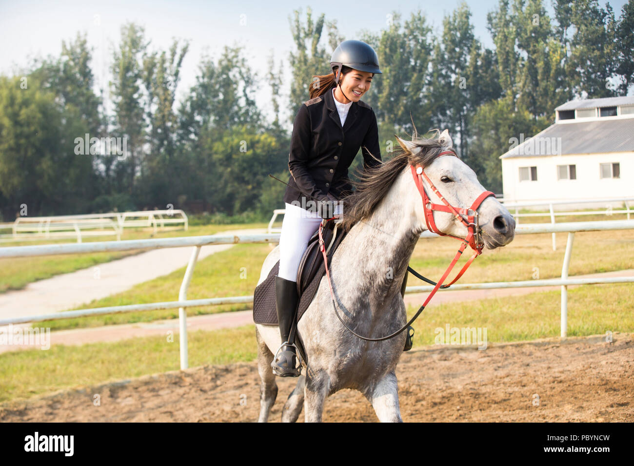 Cheerful young Chinese woman riding horse Stock Photo - Alamy