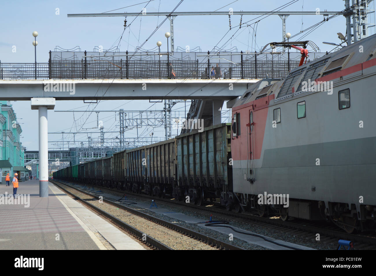 Modern locomotive carries freight train past the railway station, the ...