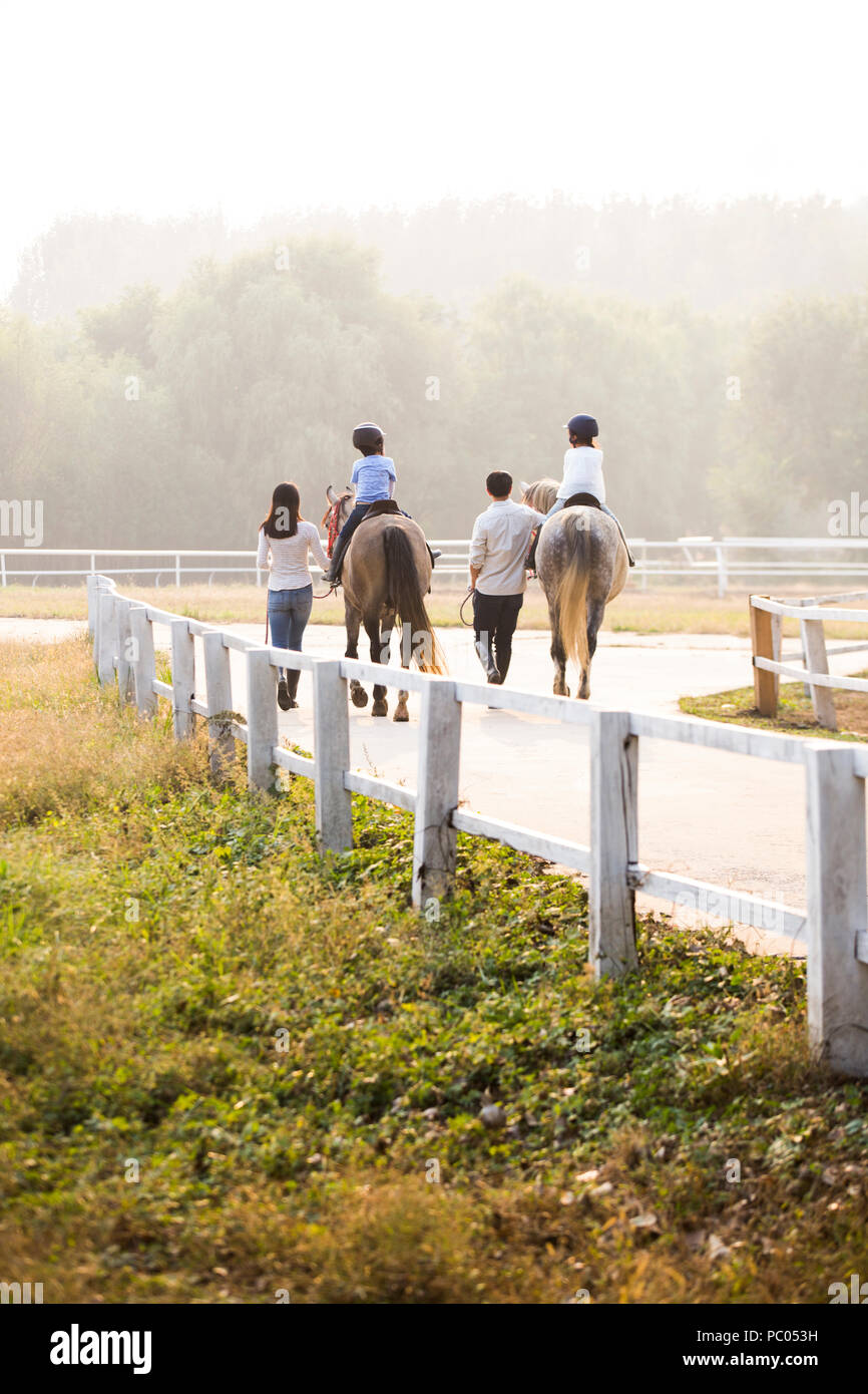 Cheerful young Chinese family riding horse Stock Photo - Alamy