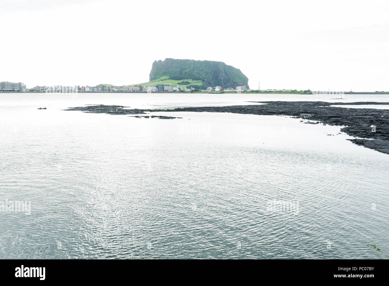 Black lava formation from white lake view to green Ilchulbong volcano ...