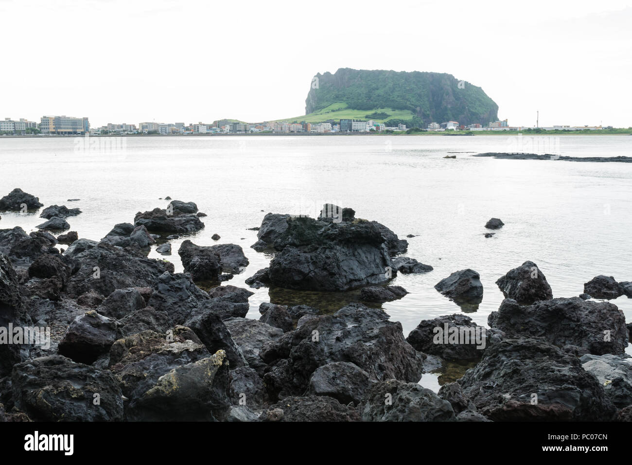 Black lava rocks with lake view to green Ilchulbong volcano crater ...