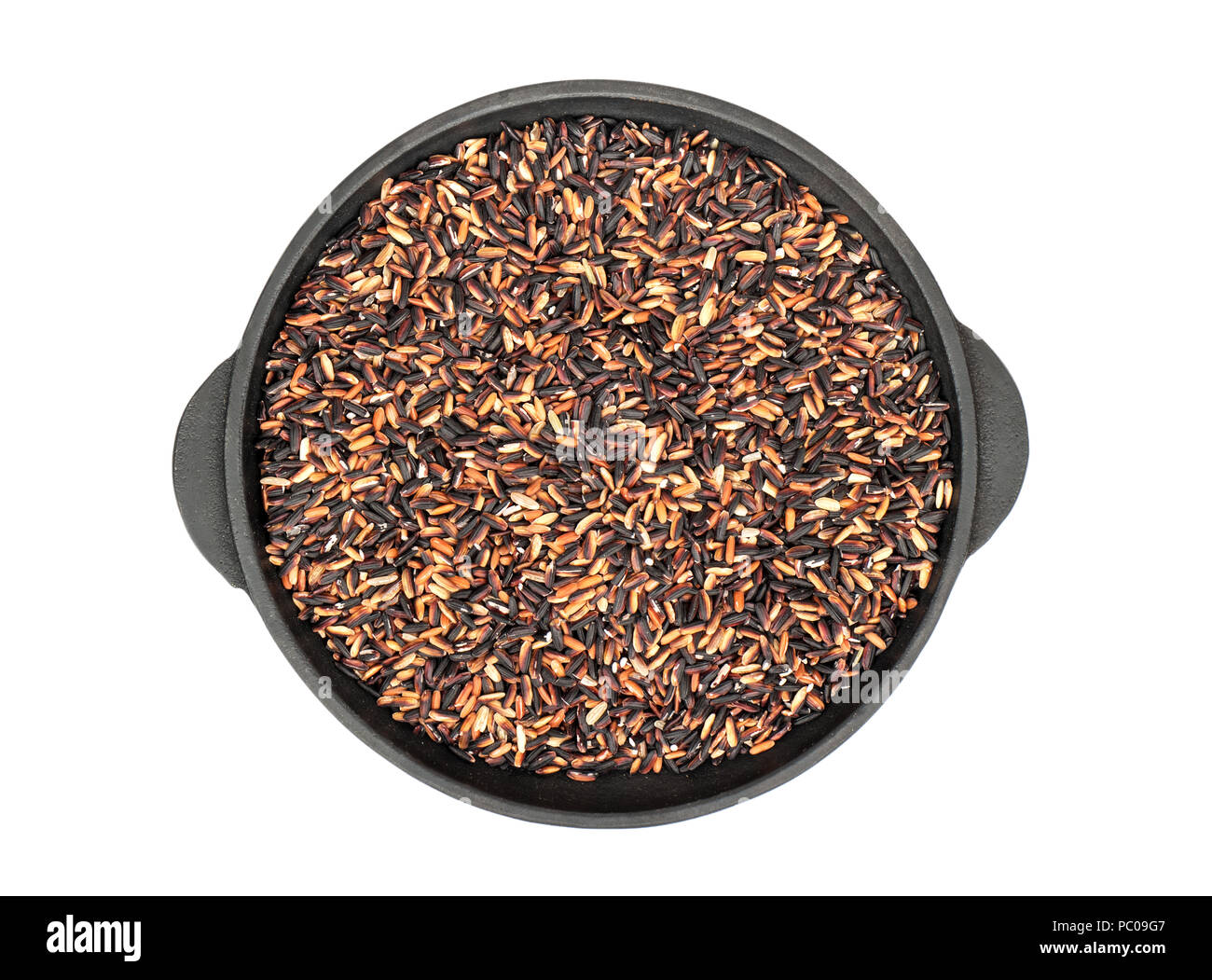 Raw black rice in a frying pan isolated on white background, top view ...