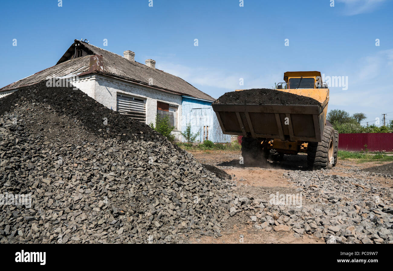 Yellow loader moving with uploaded bucket with stone gravel during road ...