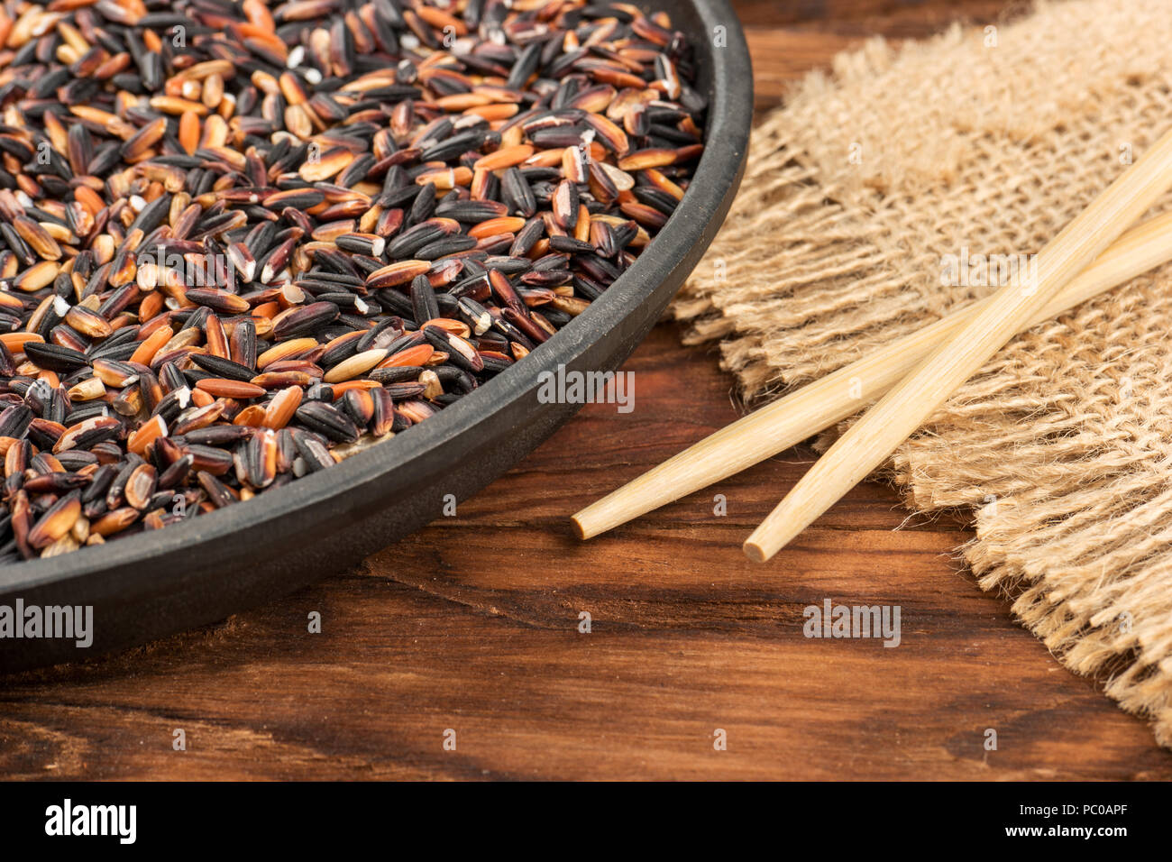 Part of frying pan with black wild rice and chopsticks on wooden ...