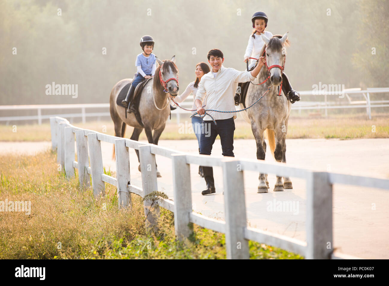Cheerful young Chinese family riding horses Stock Photo - Alamy