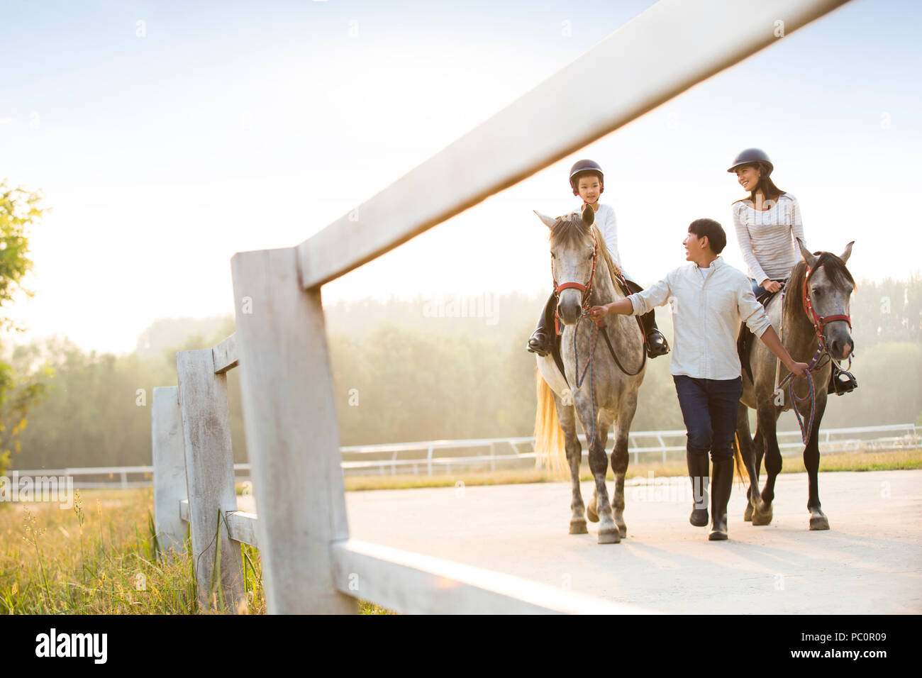 Cheerful young Chinese family riding horses Stock Photo - Alamy