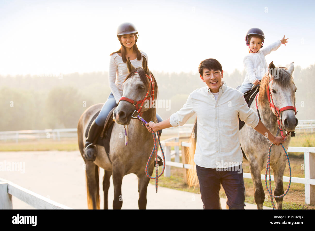 Cheerful young Chinese family riding horses Stock Photo - Alamy