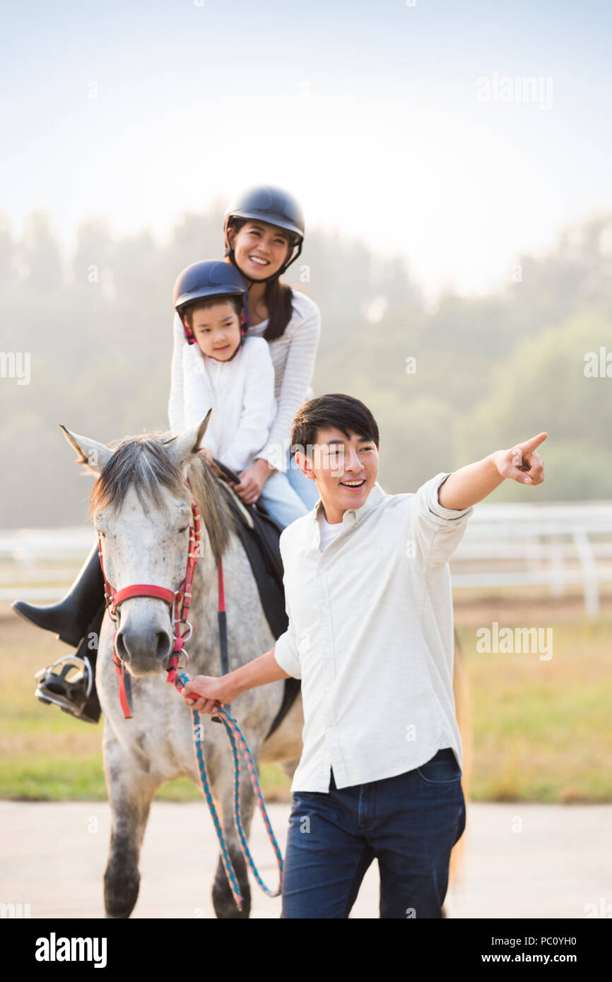 Cheerful young Chinese family riding horse Stock Photo - Alamy