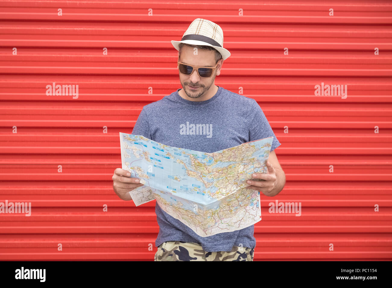 Fashionable modern tourist guy with road map against red background ...