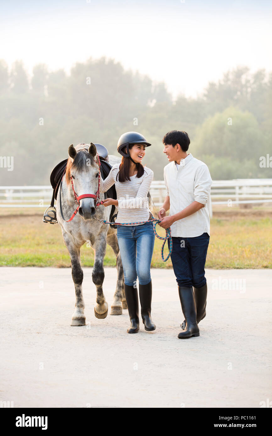 Cheerful young Chinese couple walking with horse Stock Photo - Alamy