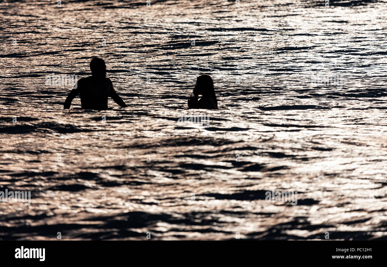 Grand Bend, Canada - July 28, 2018. A couple enjoys a late day swim in ...