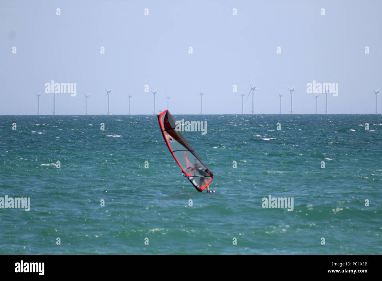 Wind surfer off Goring-by sea with wind turbines in the background ...