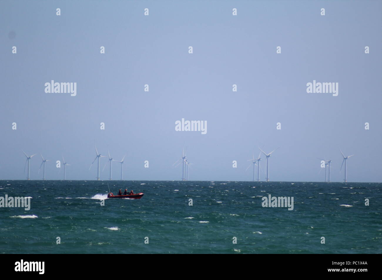 Speed boat in the sea with wind turbines on the horizon Stock Photo - Alamy