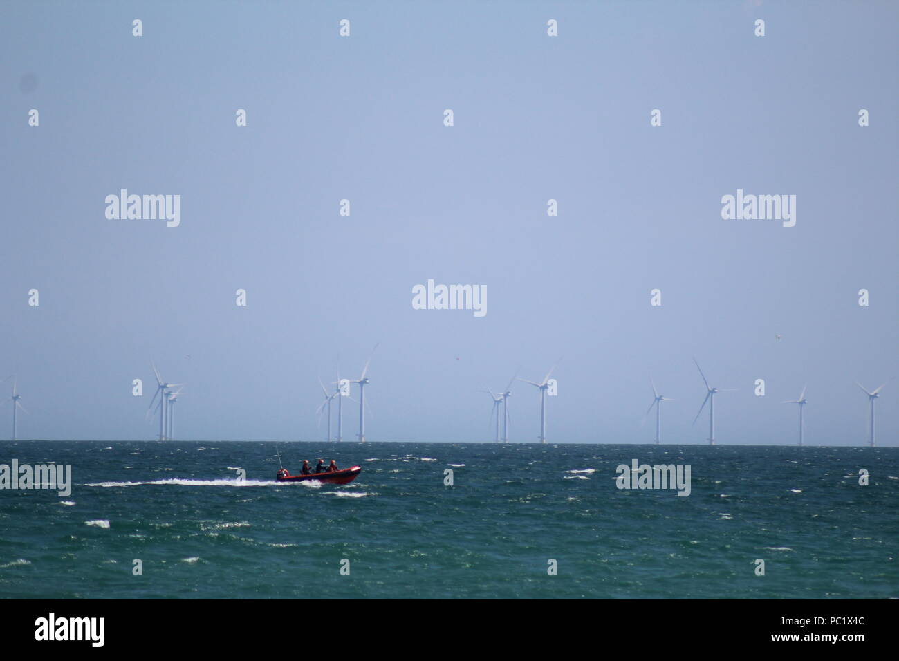Speed boat in the sea with wind turbines on the horizon Stock Photo - Alamy