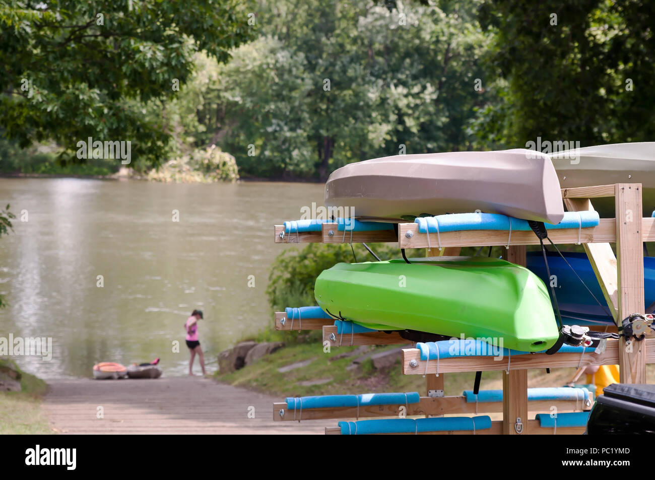 Four kayaks shown attached to a rack being taken down a ramp where a ...