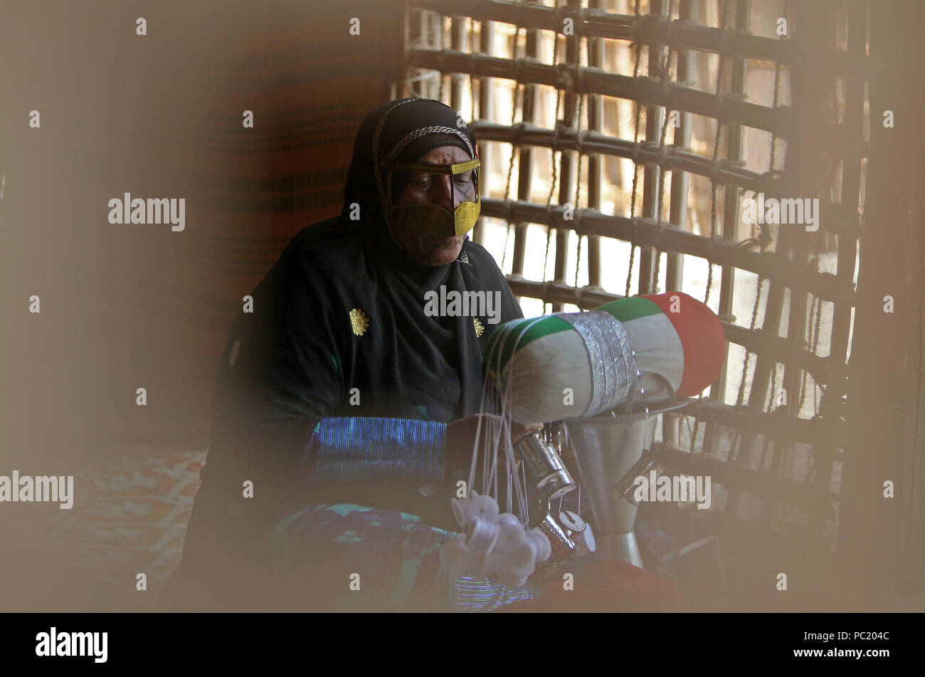 A woman sporting a metallic burqa knits Emirati flag in the heritage ...