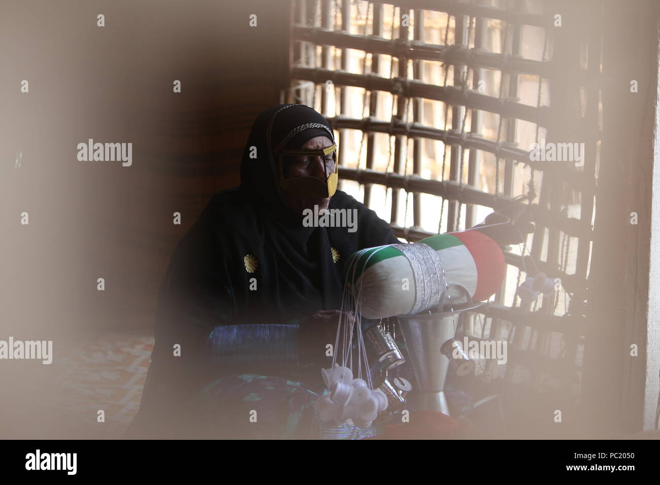 A woman sporting a metallic burqa knits Emirati flag in the heritage ...