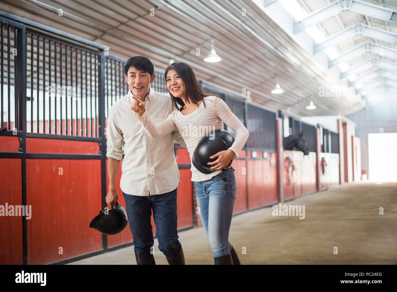 Cheerful young Chinese couple in horse stable Stock Photo - Alamy