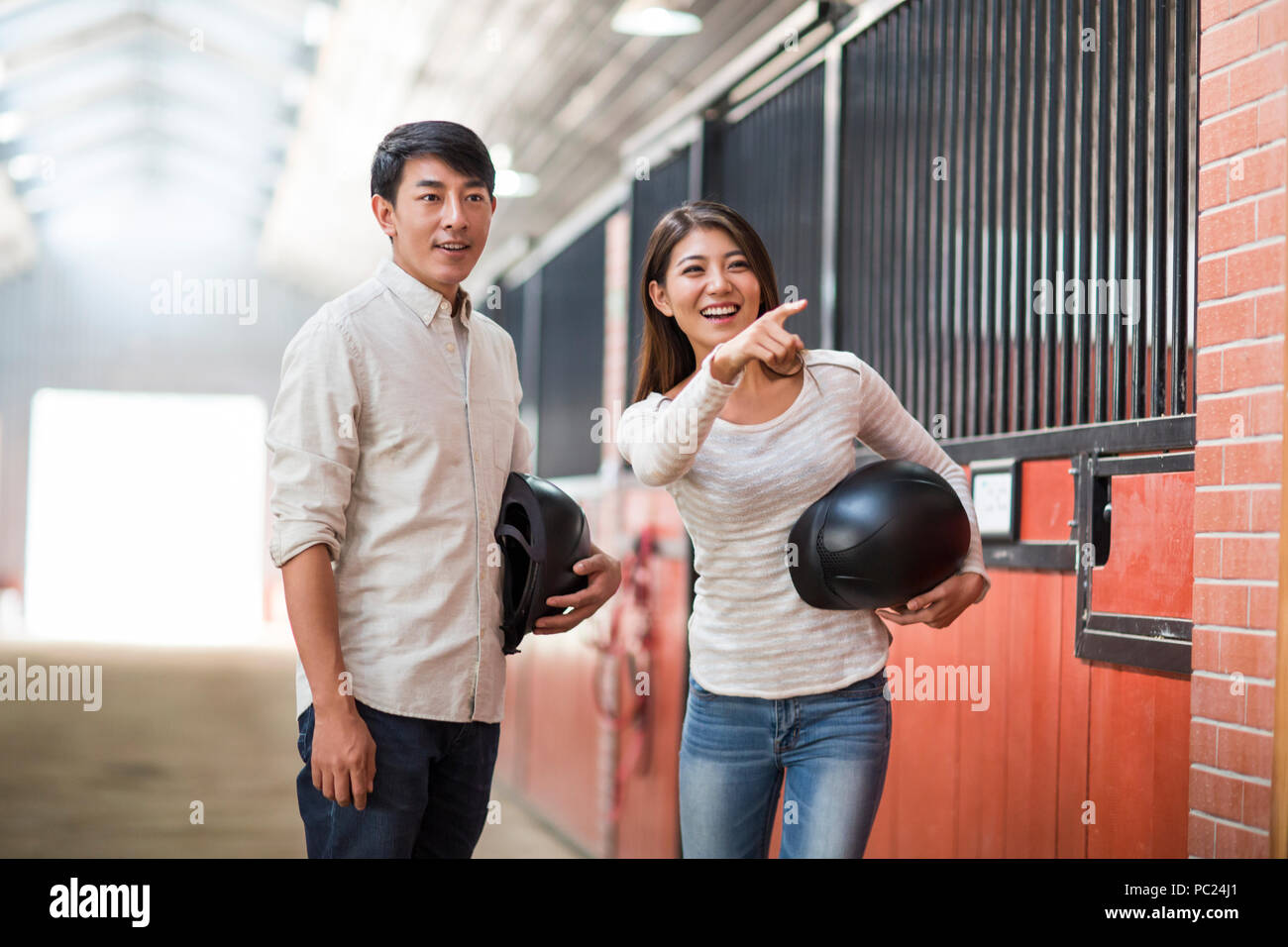 Cheerful young Chinese couple in horse stable Stock Photo - Alamy